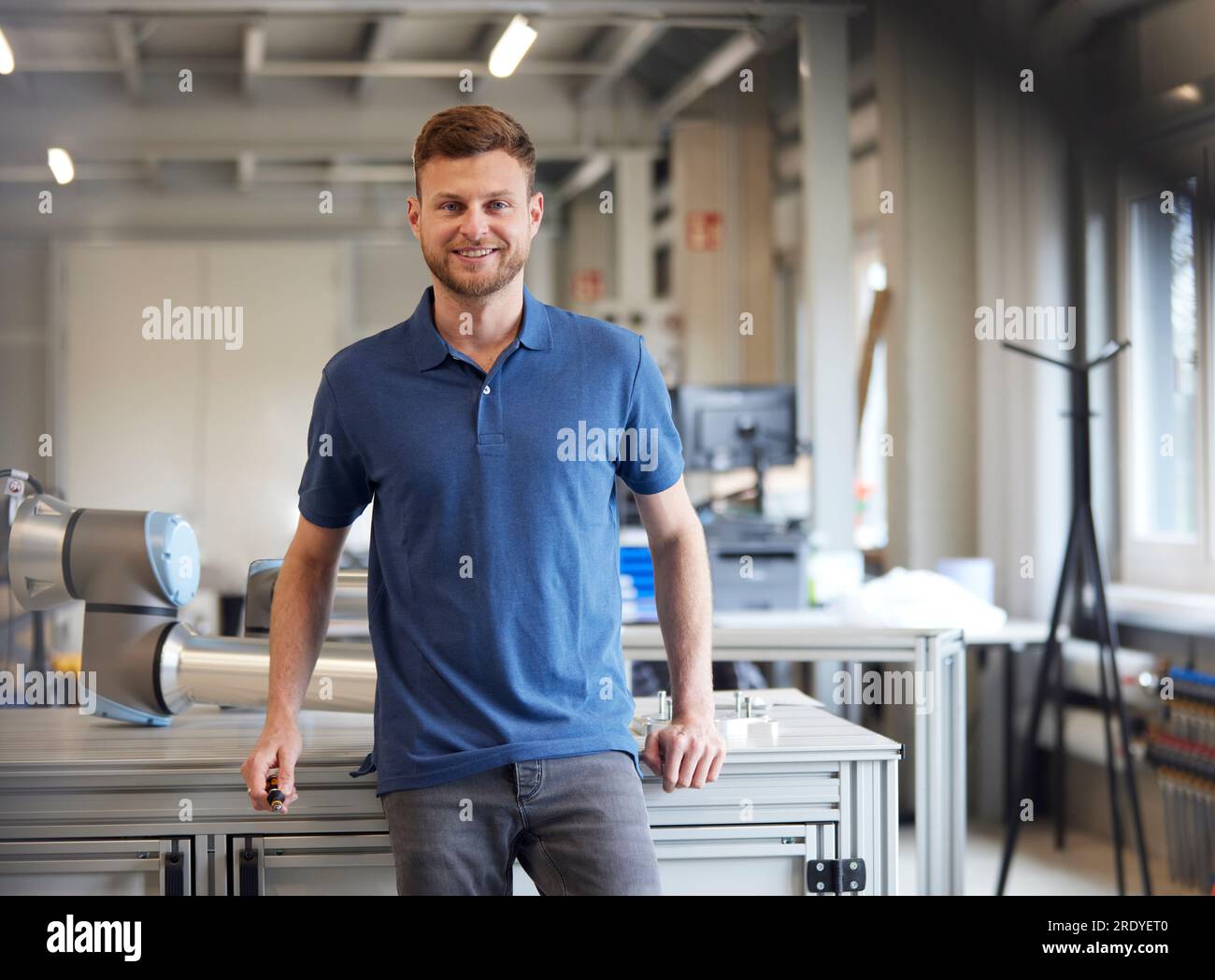 Smiling technician leaning on table in industry Stock Photo - Alamy