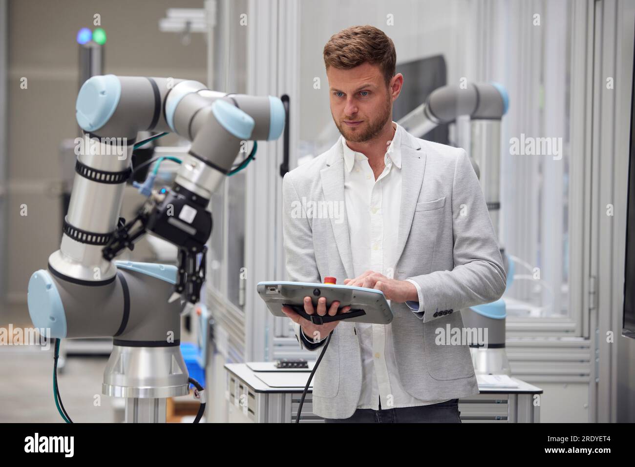 Engineer operating modern machine in robot factory Stock Photo - Alamy