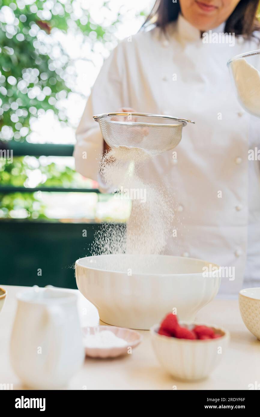 Chef sieving flour through siever Stock Photo - Alamy