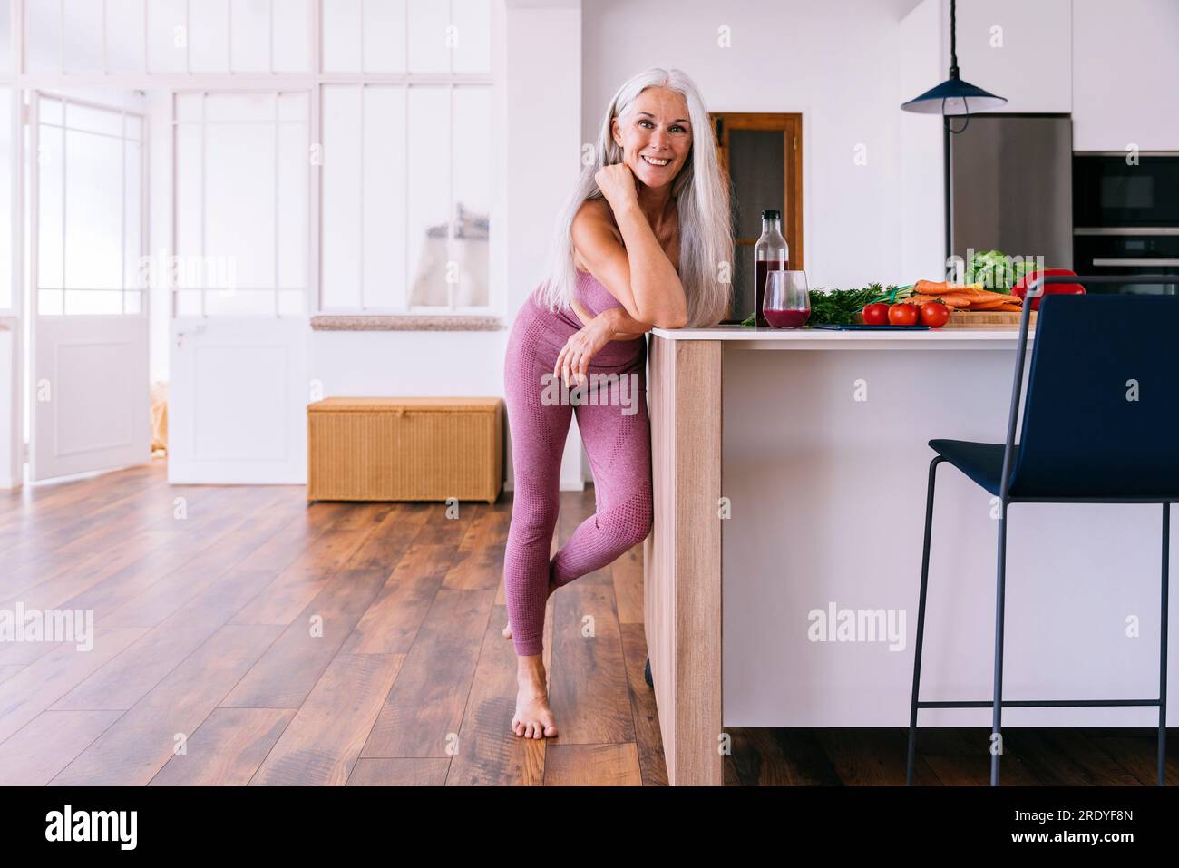 Happy mature woman leaning on kitchen counter at home Stock Photo - Alamy