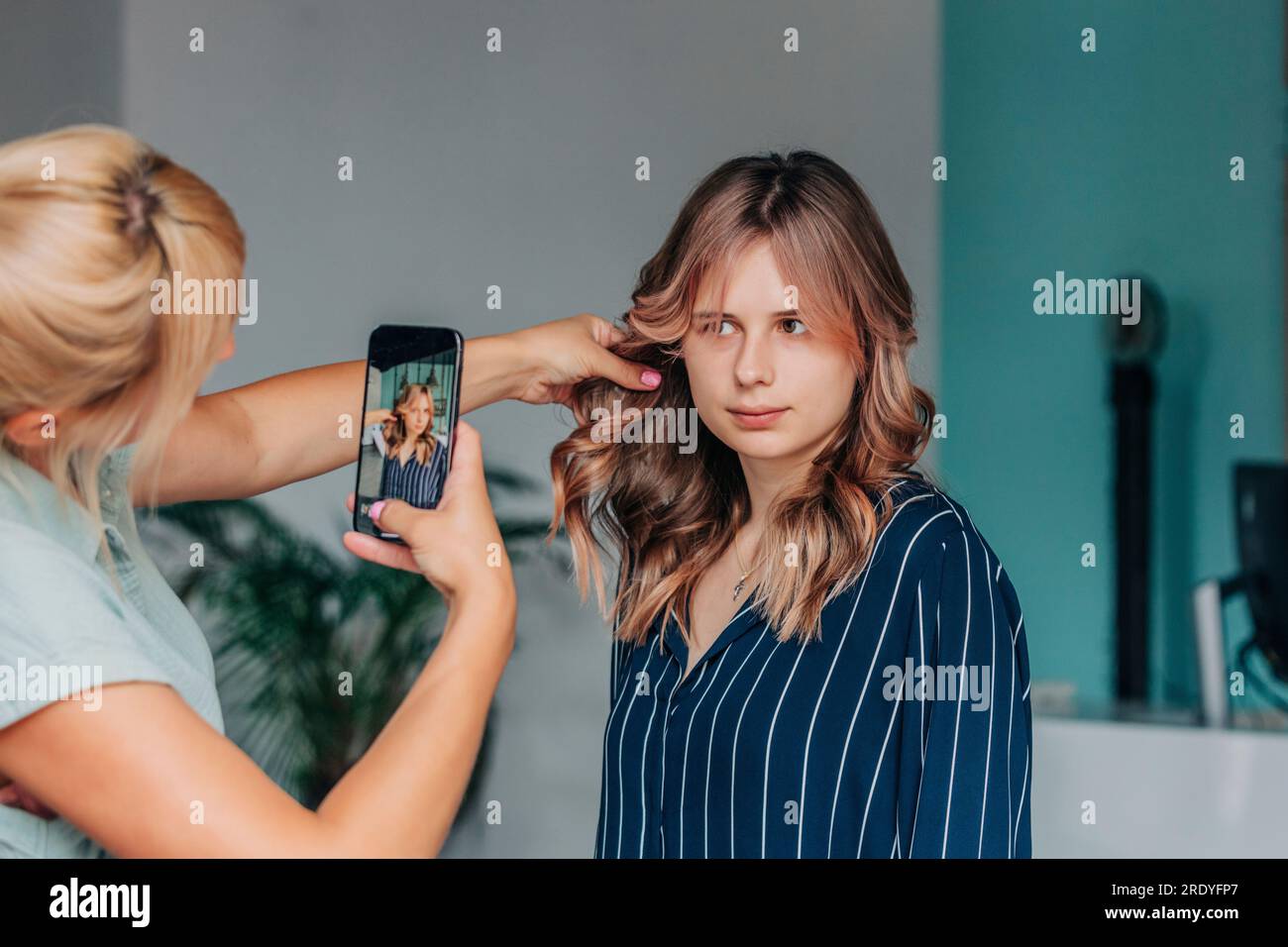 Hairdresser taking picture of young client in salon Stock Photo - Alamy