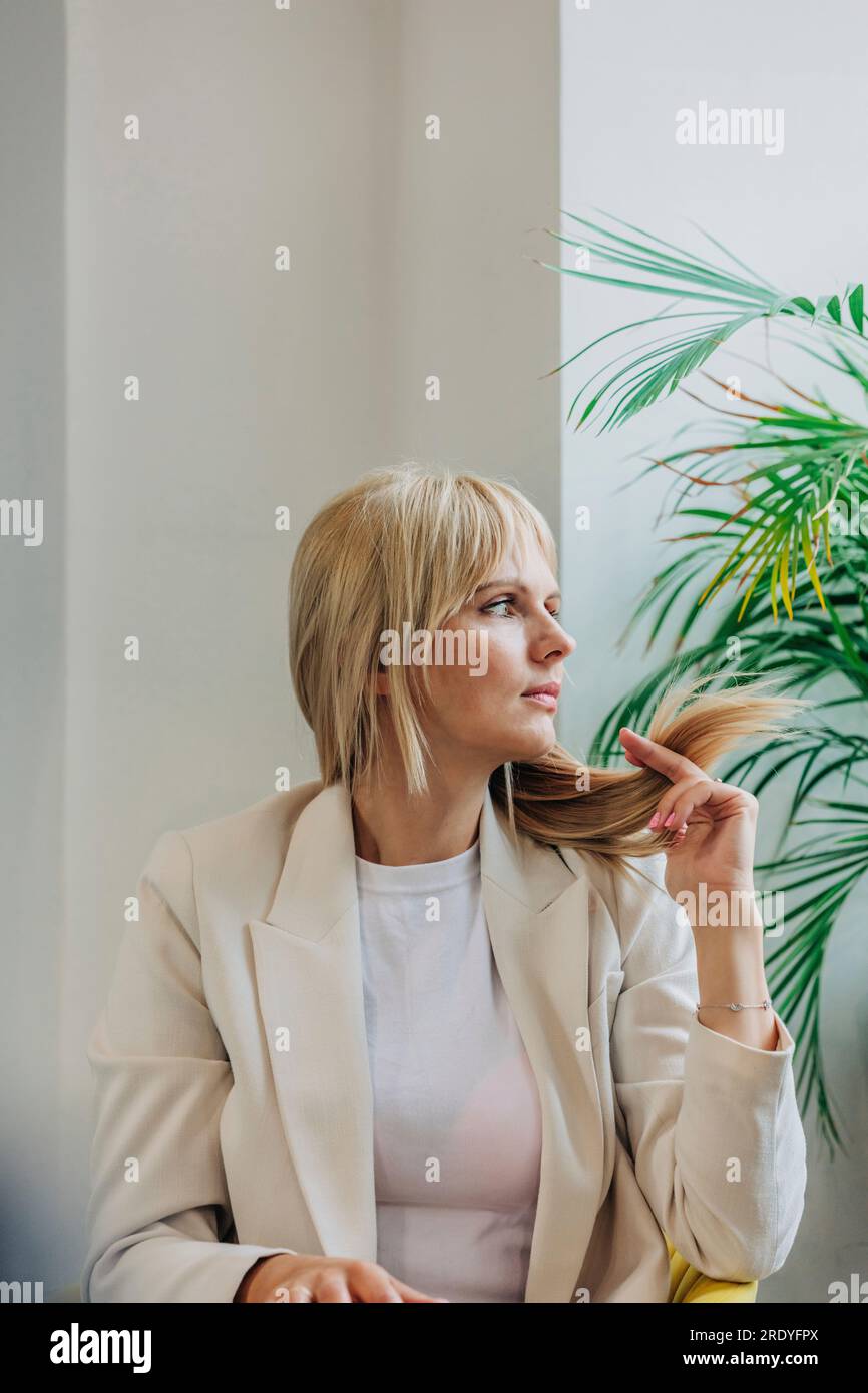 Blond woman with hand in hair wearing blazer Stock Photo - Alamy