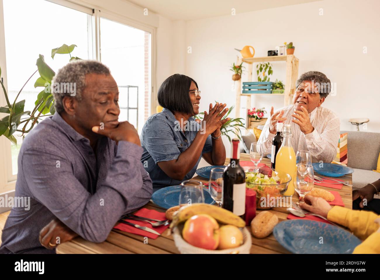 Multi-cultural senior friends talking to each other at dining table in ...