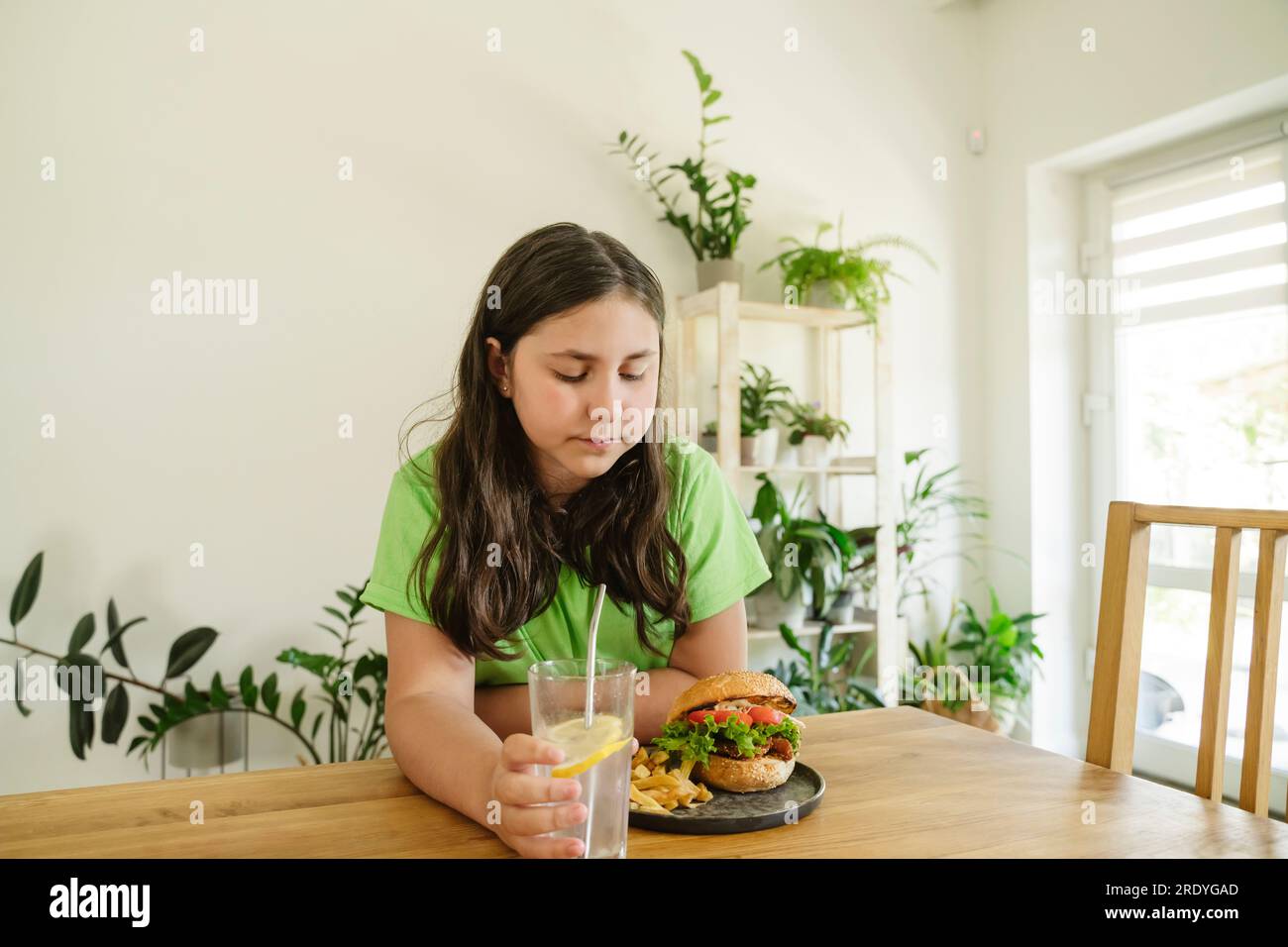 Girl staring at burger on table at home Stock Photo - Alamy