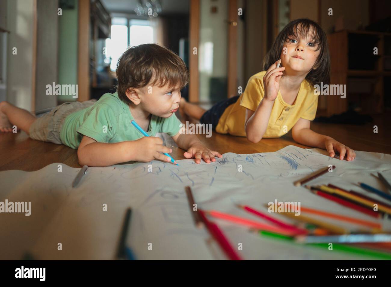 Brothers drawing with colored pencils lying on floor at home Stock ...