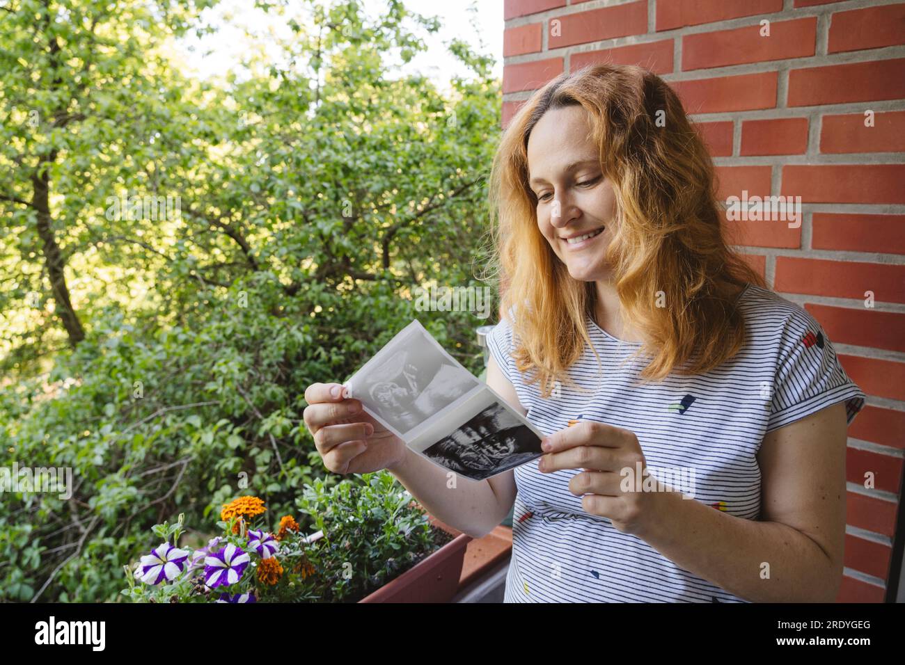 Smiling pregnant woman looking at ultra scan report in balcony Stock ...