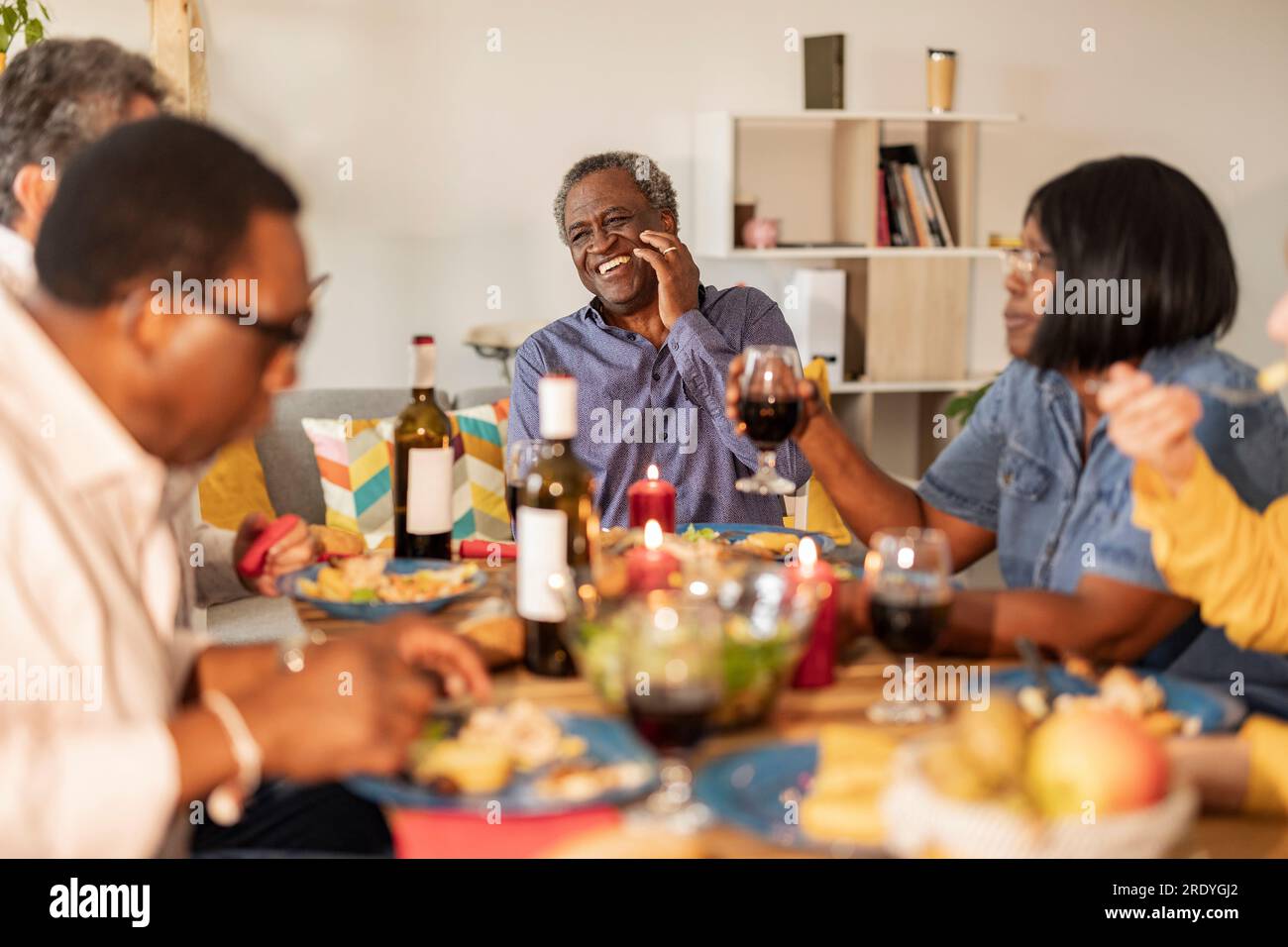 Happy senior man laughing with friends having food at dinner party ...