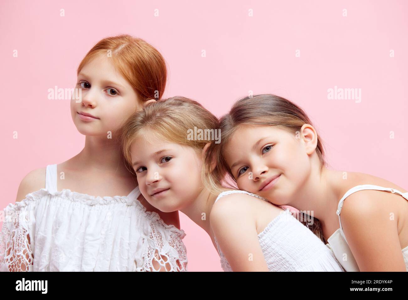 Three beautiful, cute little girls, children in ponytails, in white ...
