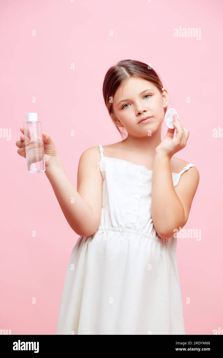 Portrait of pretty little girl, child in white dress applying face ...
