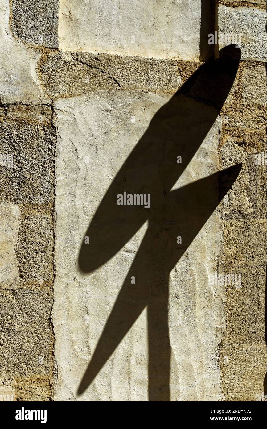 Shadow of a road sign casting on a textured wall under bright sunlight ...