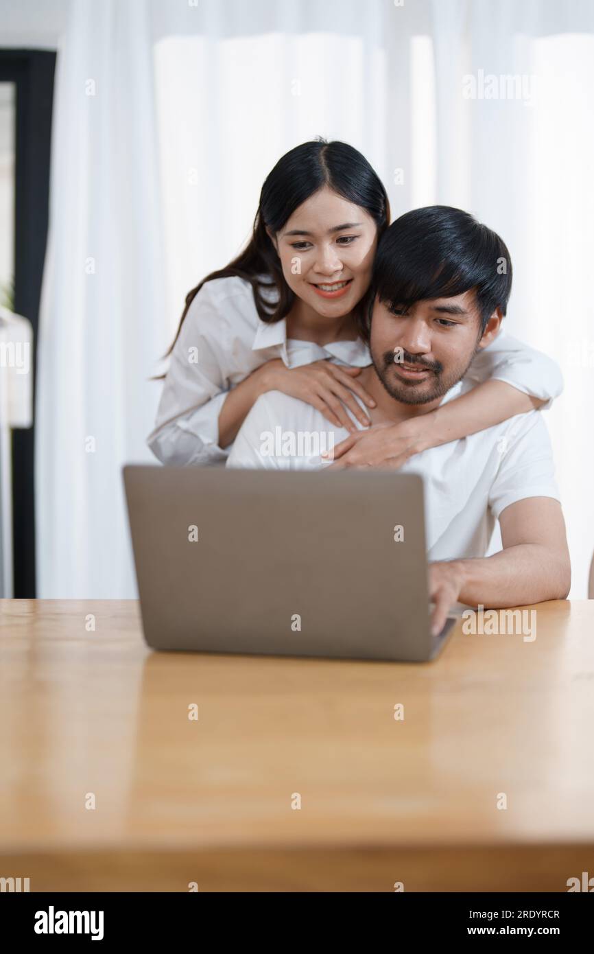 Young married couple showing happy smiling faces and using computers ...