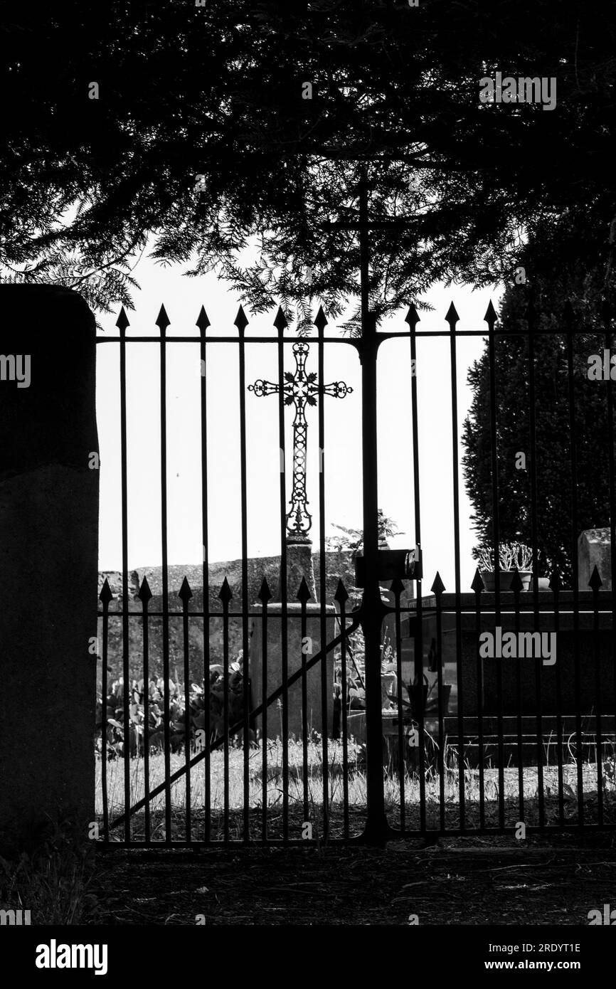 Black and white image of ornate gates with a cross at a cemetery ...