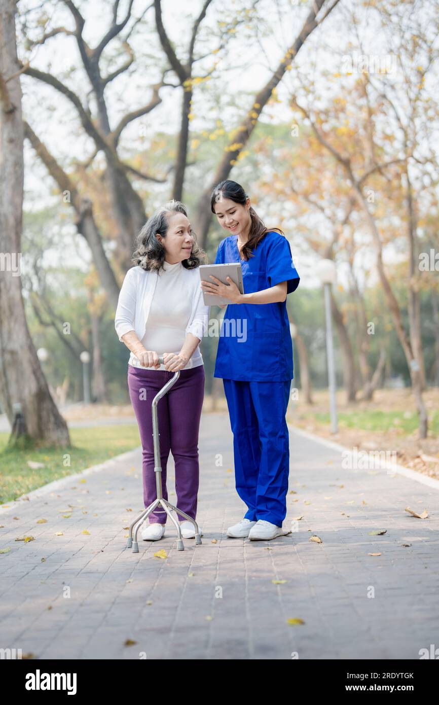 Patient care,, young Asian female nurse caring for with a cane and ...