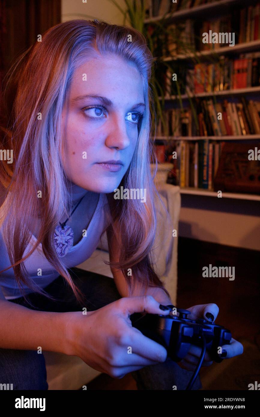 A young woman intently stares at the television while playing a video ...