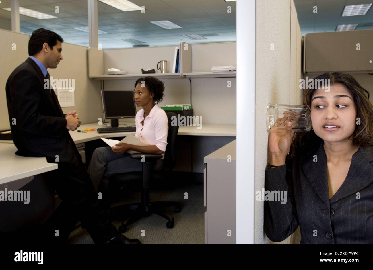 A female worker listens in on her co-workers through a cubicle wall ...