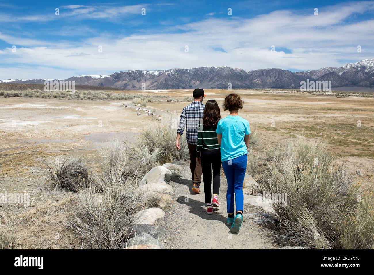 Father walks outside on a trail with two daughters following Stock ...
