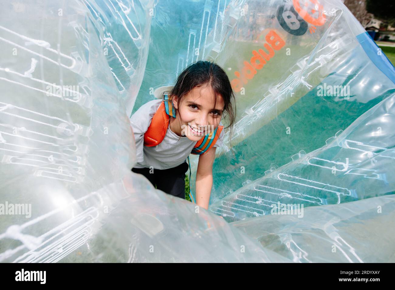 Smiling tween girl is strapped into an inflatable ball Stock Photo - Alamy