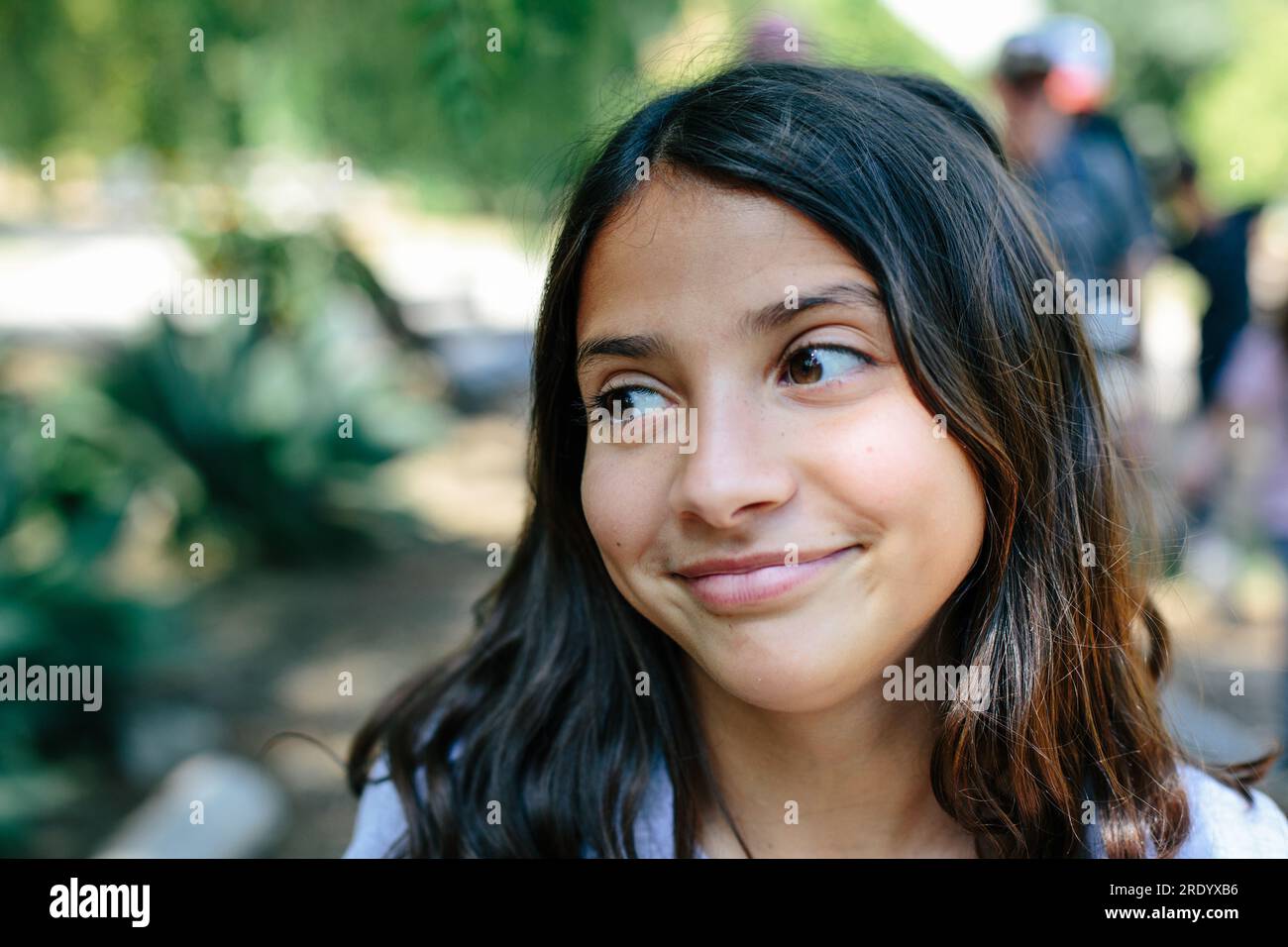 Tween girl smiles and looks to her right during a portrait outside ...