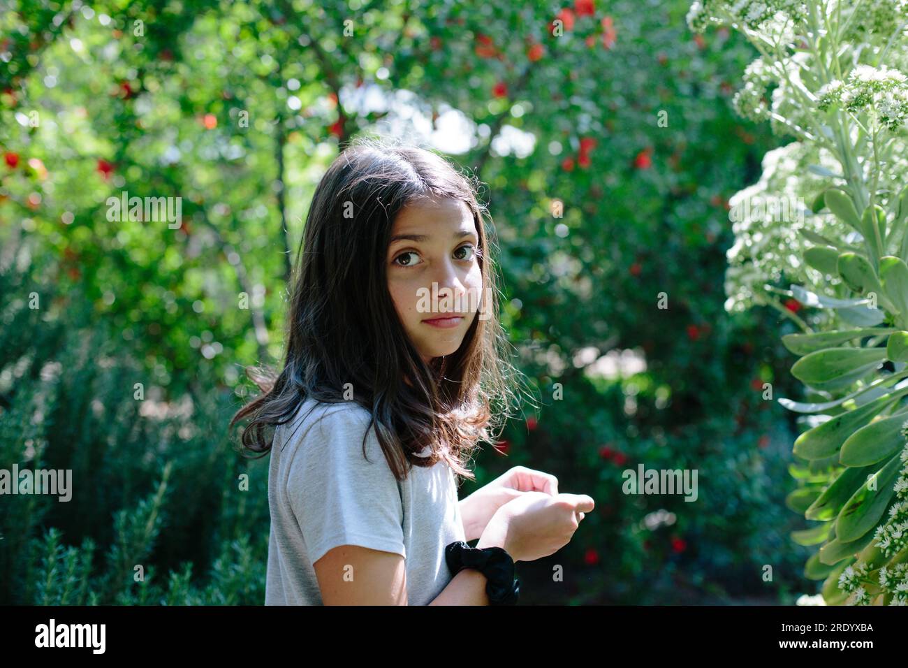 Tween girl outside in nature looks over shoulder at camera Stock Photo ...