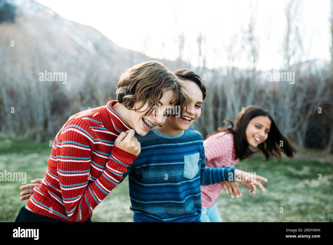 Brother with two sisters laughing together while outside Stock Photo ...
