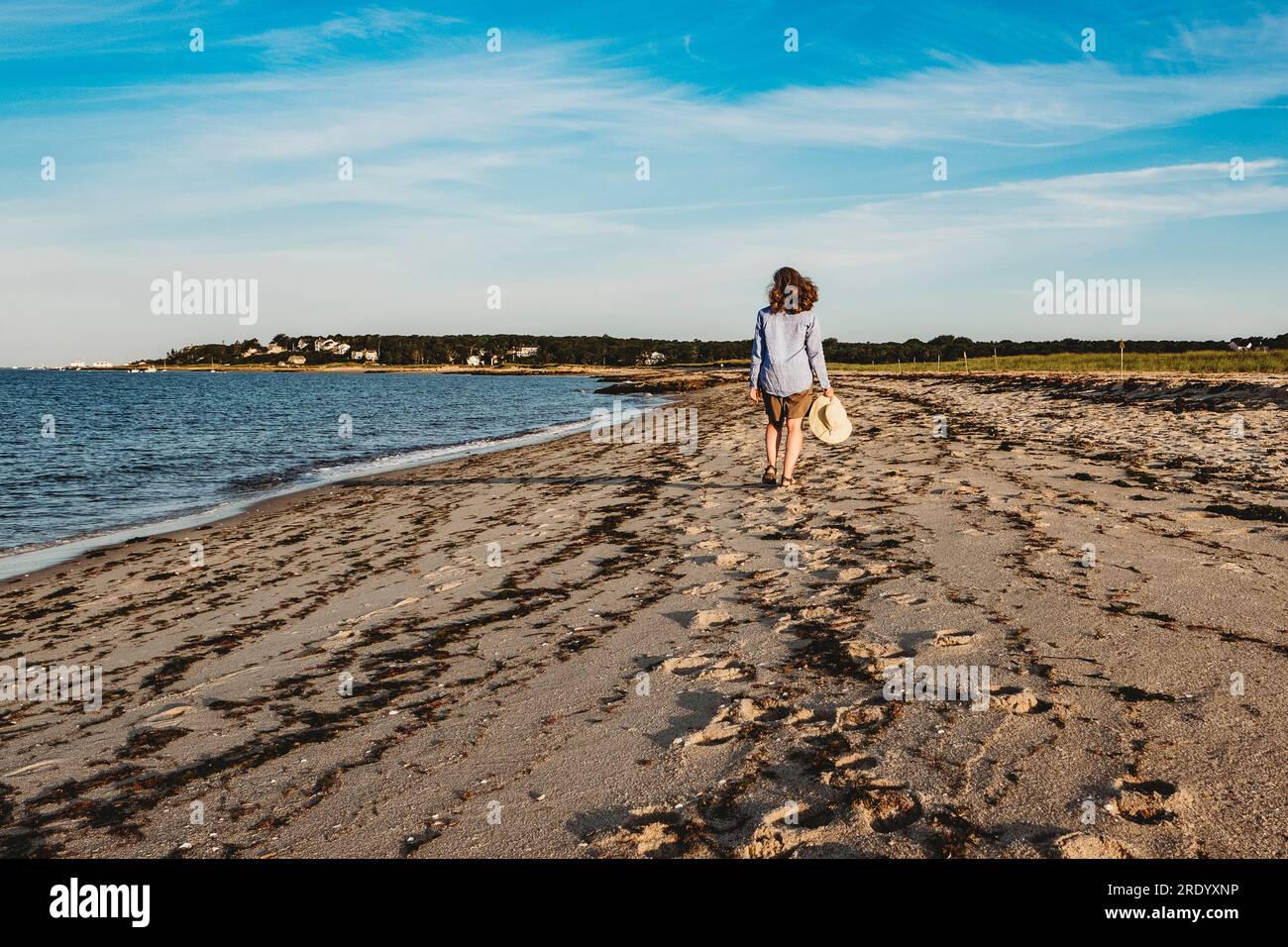 Mature woman walking on Cape Cod beach in summer with hat in hand Stock ...