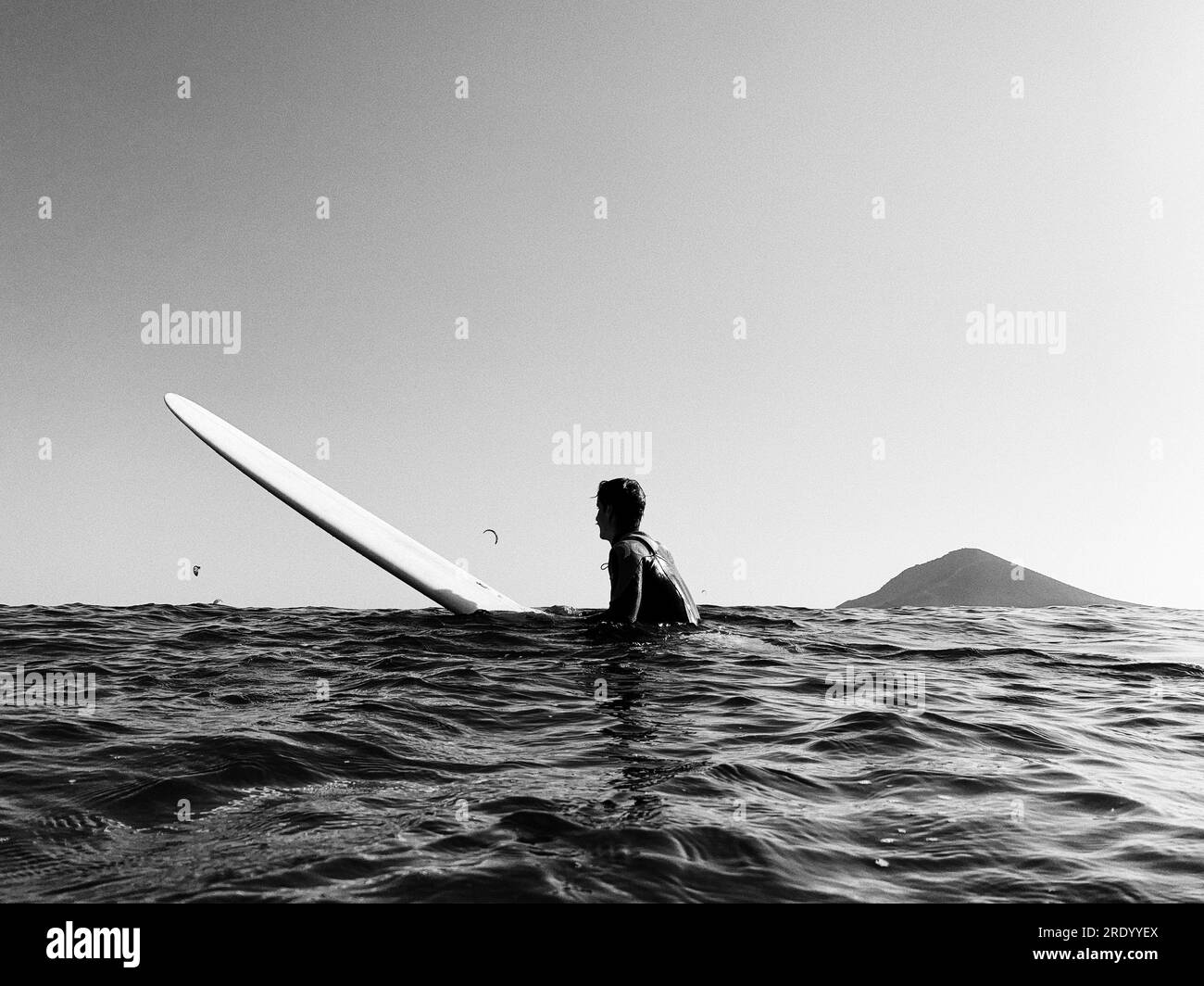 Pulled back view of surfer sitting on surfboard, black and white Stock ...