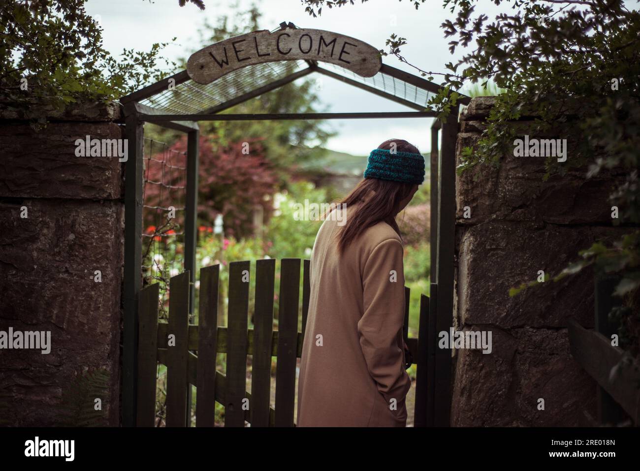 Person enters lush garden gate with welcome sign Stock Photo - Alamy