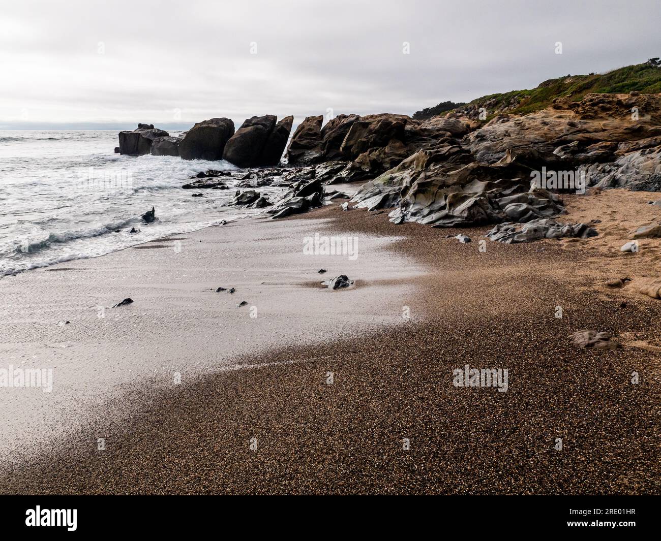 Waves receding on rocky beach Stock Photo - Alamy