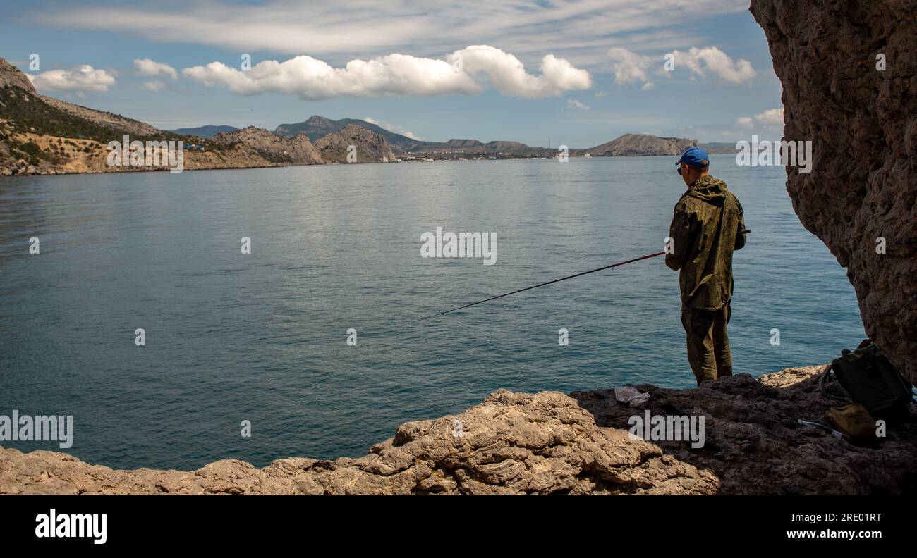 Fisherman fishing from a cliff in the sea Stock Photo - Alamy