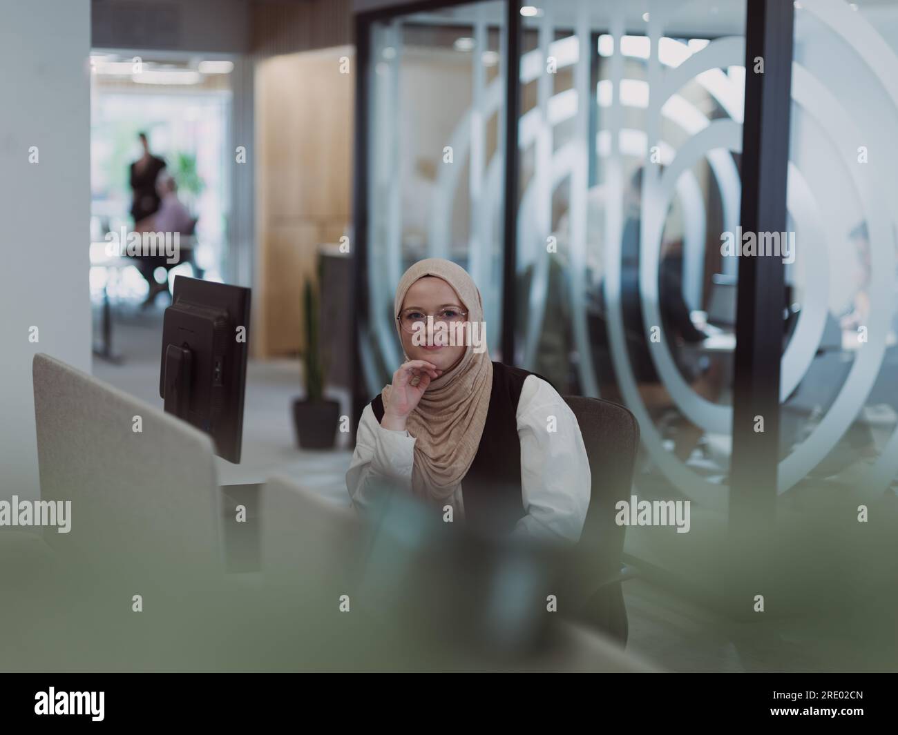 In a modern office, a young Muslim entrepreneur wearing a hijab sits ...