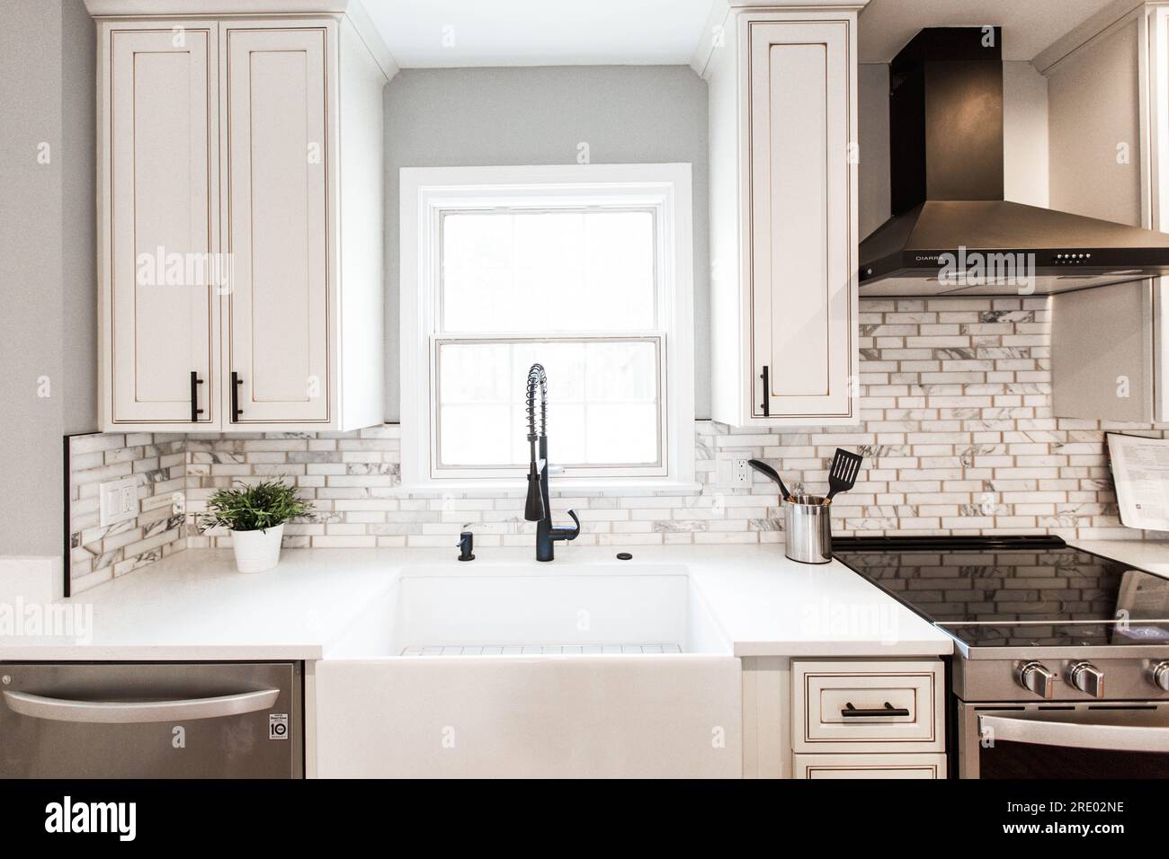 White Kitchen Sink and Cabinets with Black Stove Stock Photo - Alamy