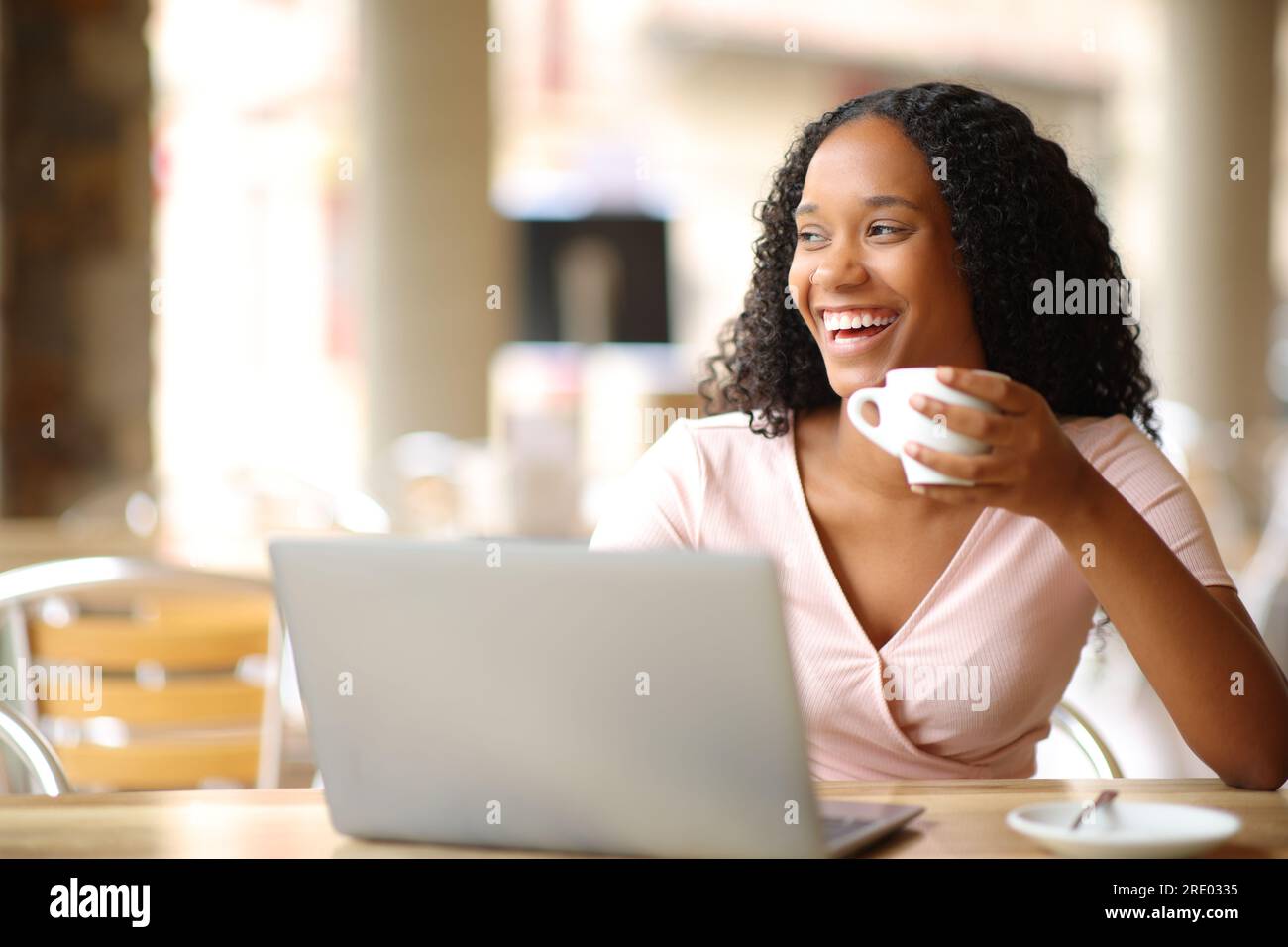 Happy black woman with laptop drinking coffee and laughing looking away ...