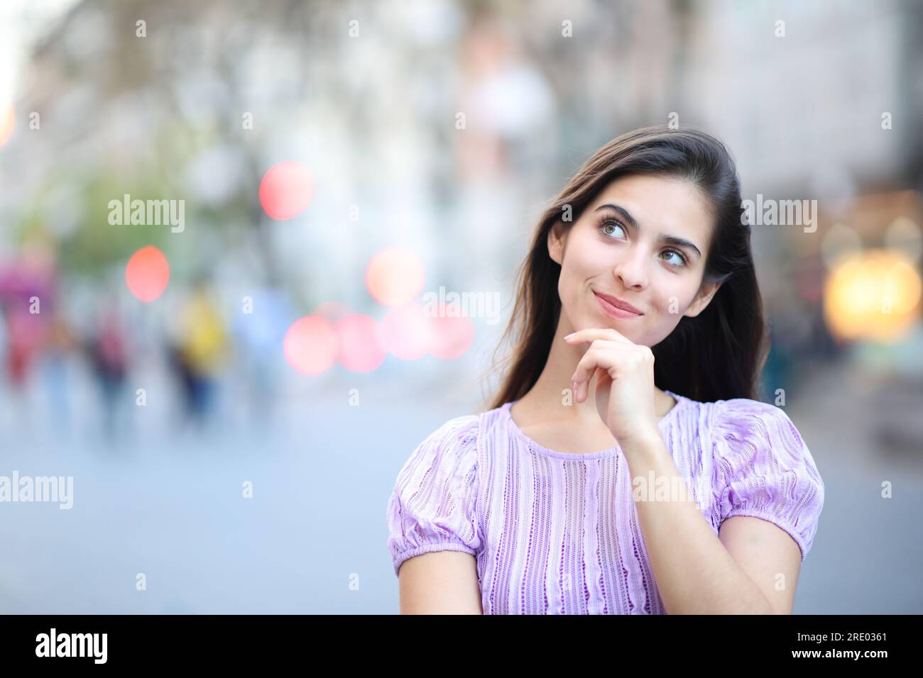 Front view portrait of a woman thinking looking at side in the street ...
