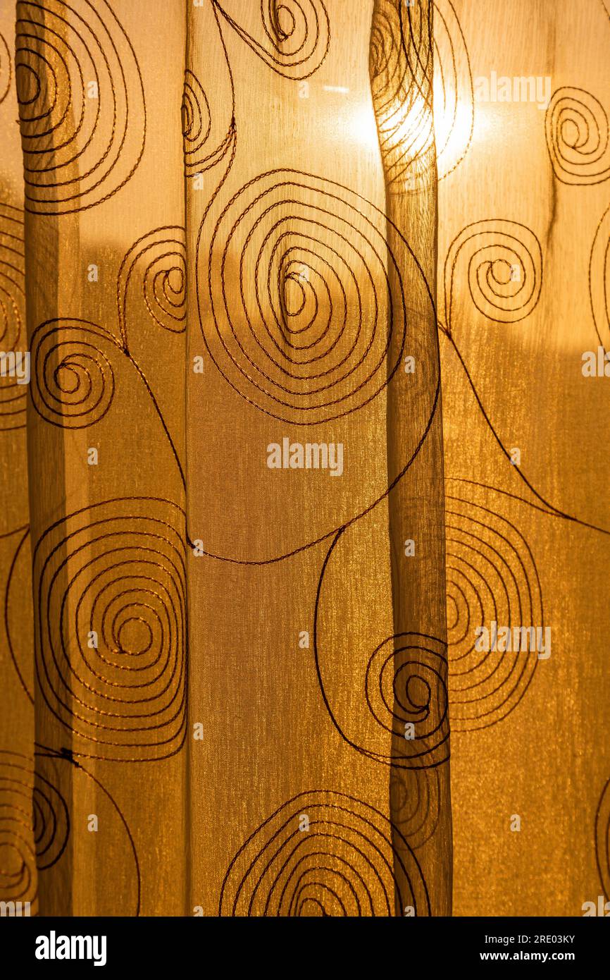 Setting sun seen through curtains with spiral patterns Stock Photo - Alamy