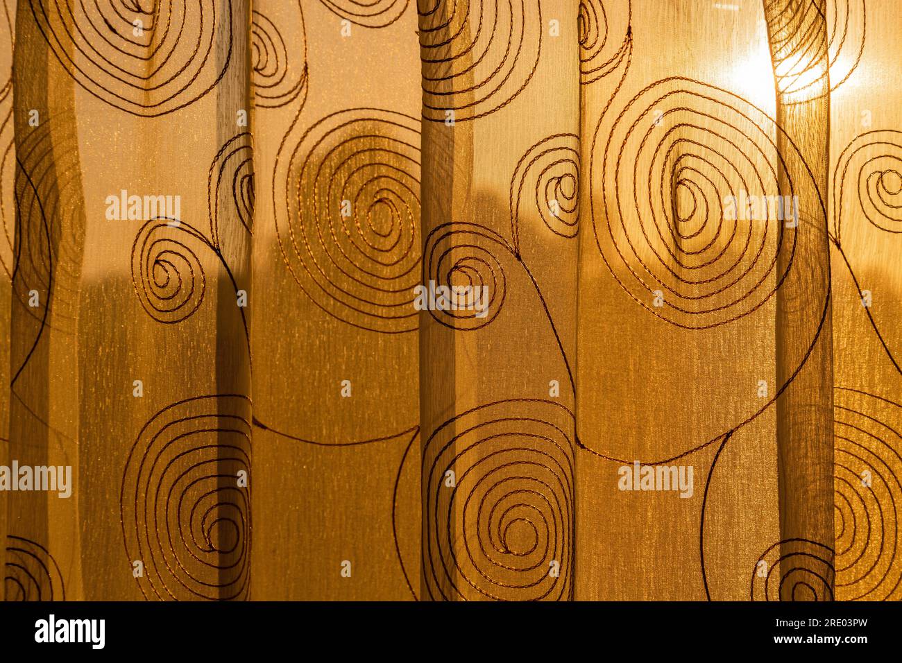 Setting sun seen through curtains with spiral patterns Stock Photo - Alamy