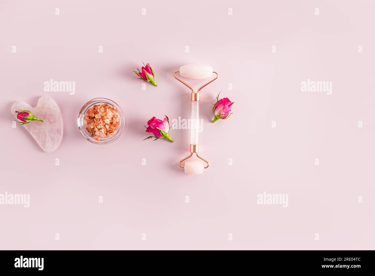Rose quartz massager, gua sha scraper, salt in a bowl and small ...