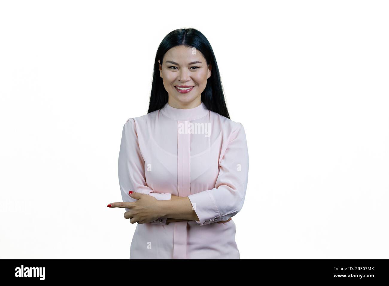 Portrait of a young asian woman with crossed arms pointing at something ...