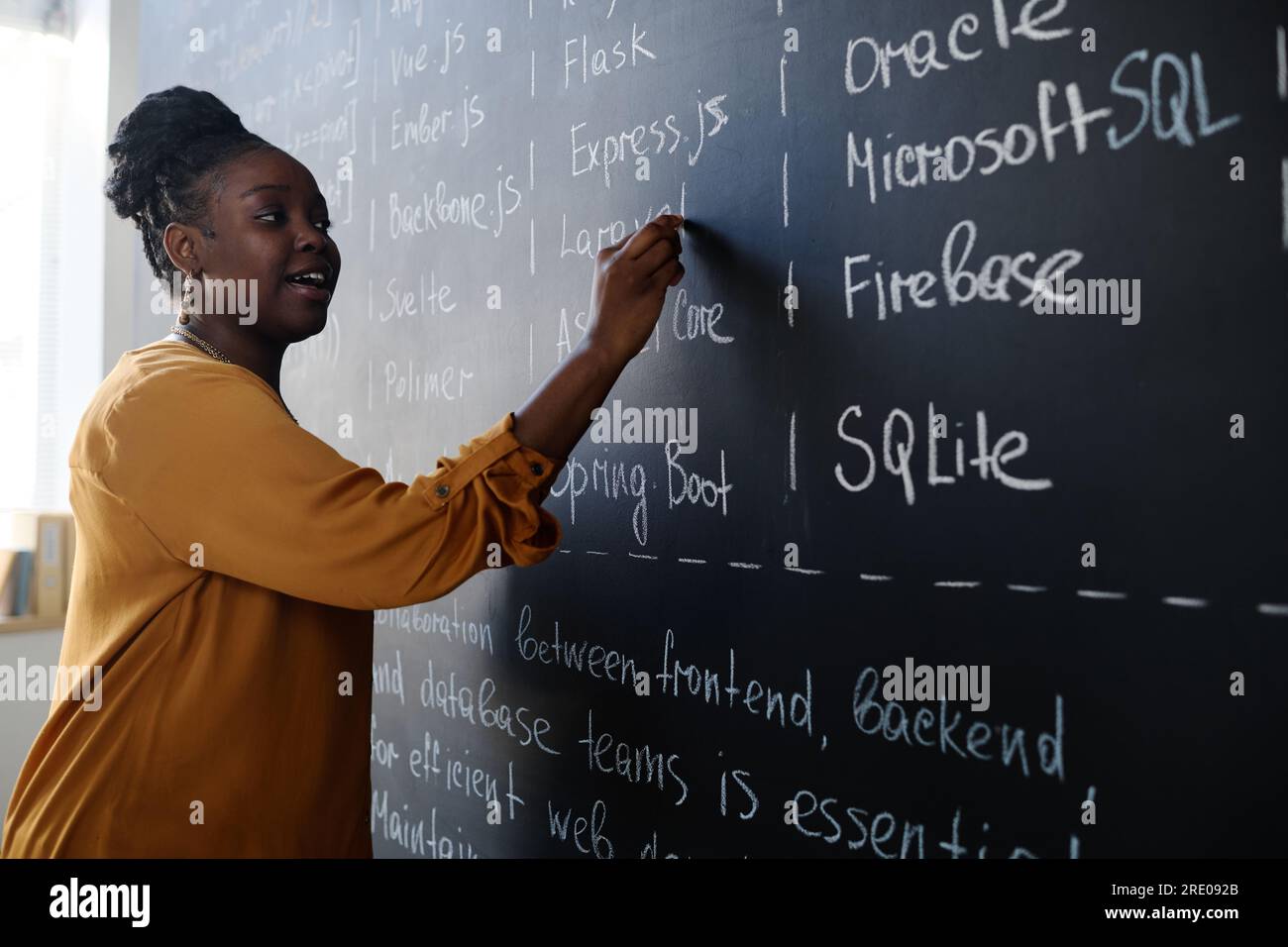 African American woman writing on blackboard, she teaching IT lesson at ...
