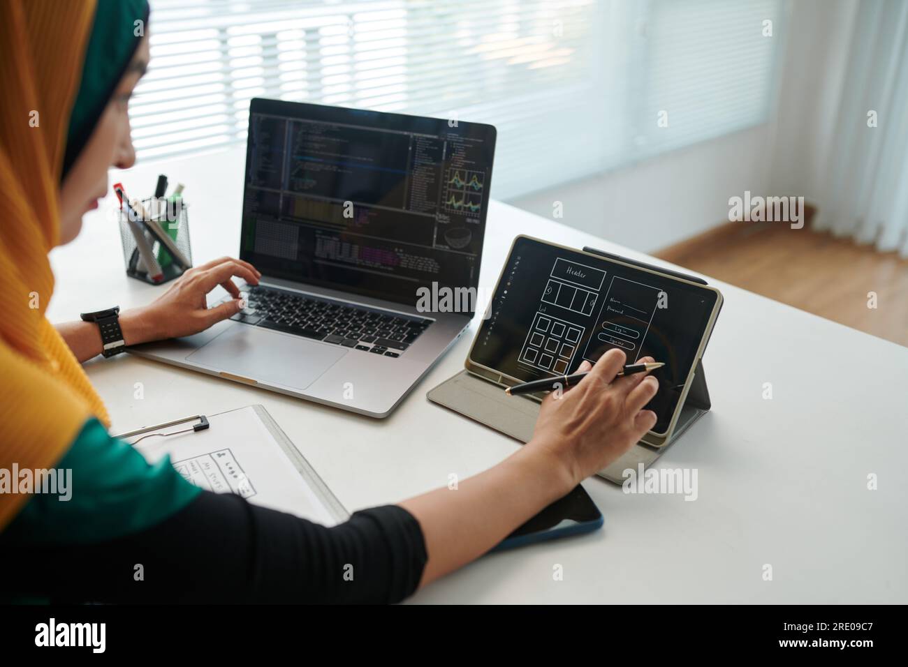 Front end developer checking wireframe on table screen when coding Stock Photo - Alamy