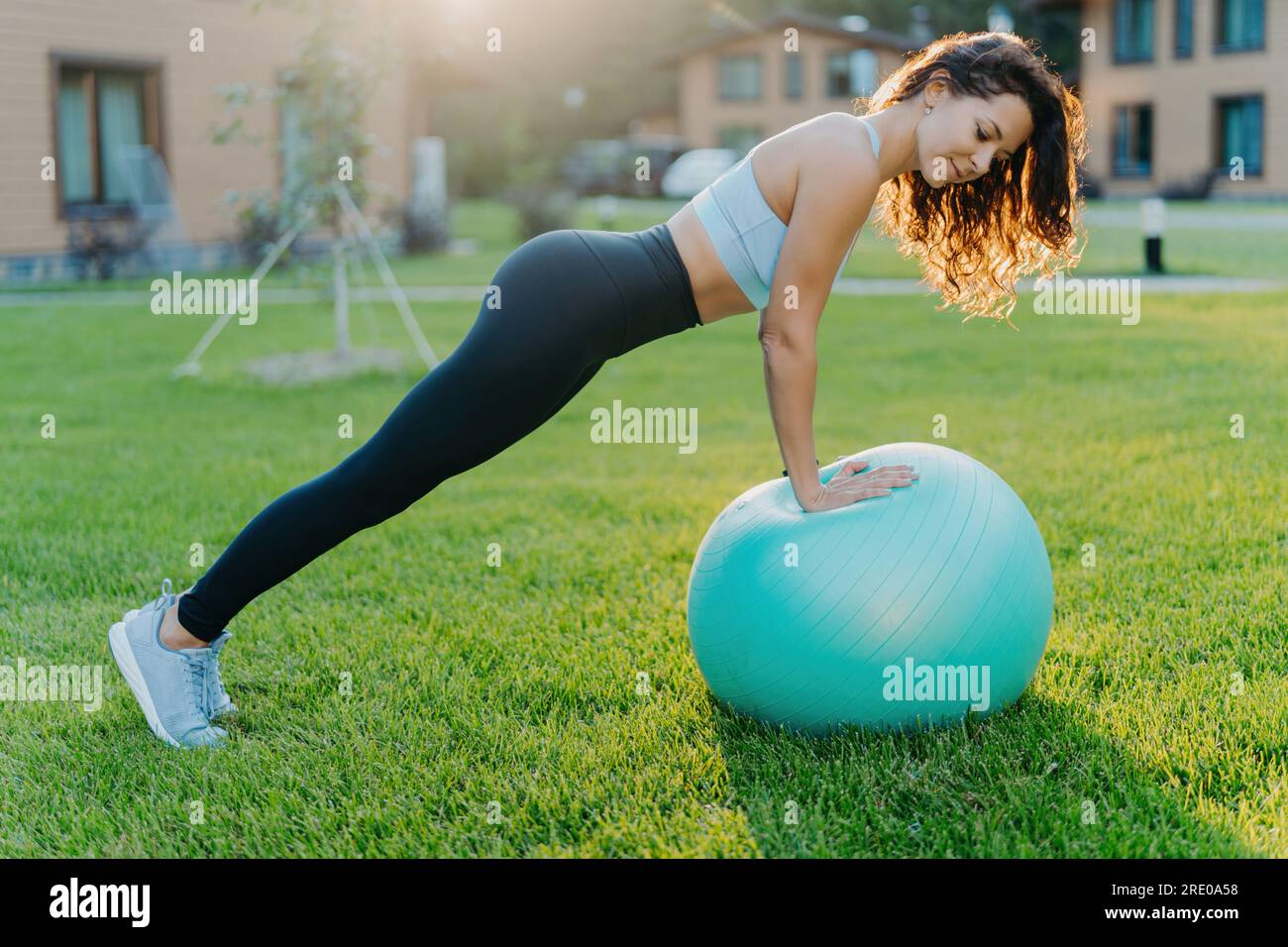 Active woman trains outdoors, does gymnastics with fit ball, wears ...