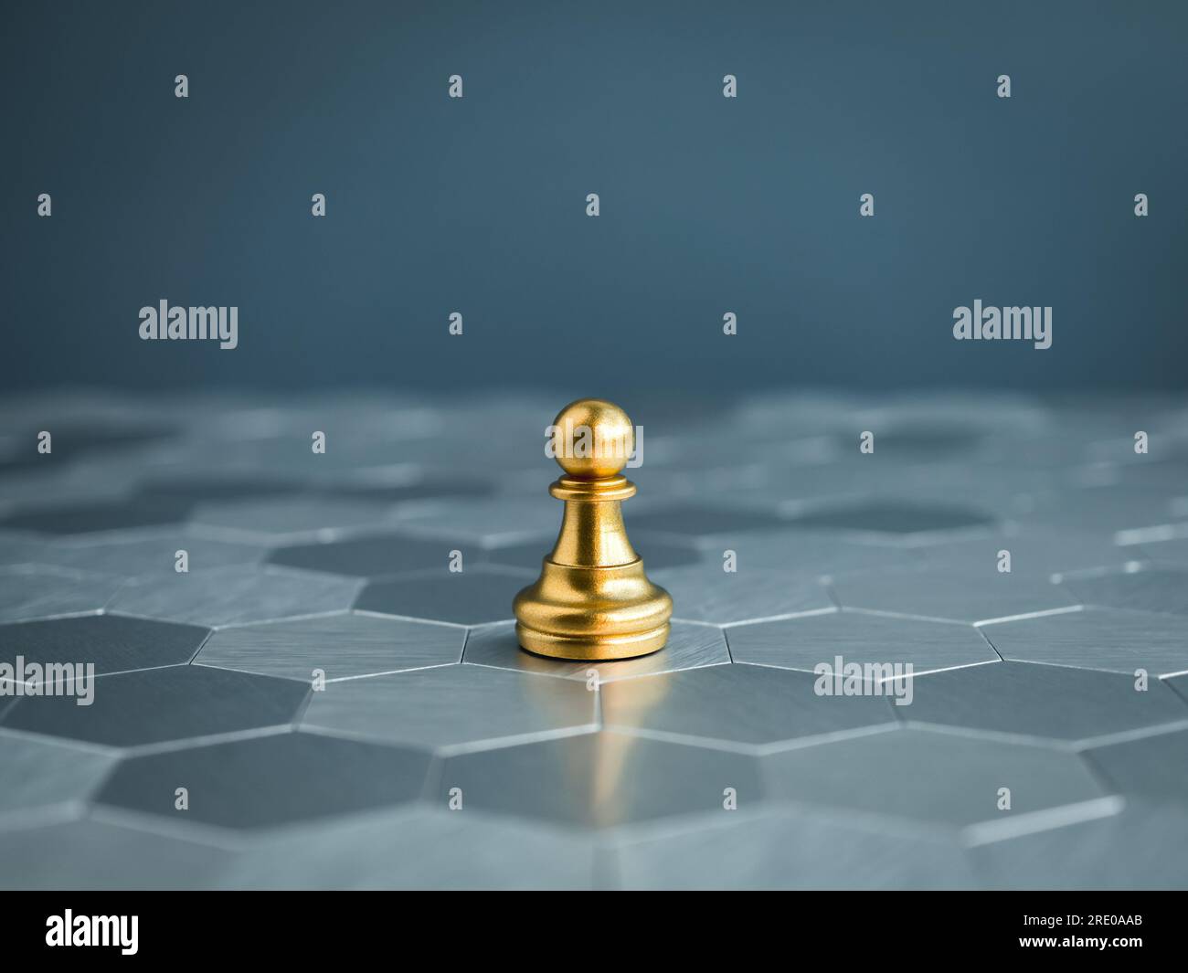 The small golden pawn chess piece standing alone on hexagon pattern ...