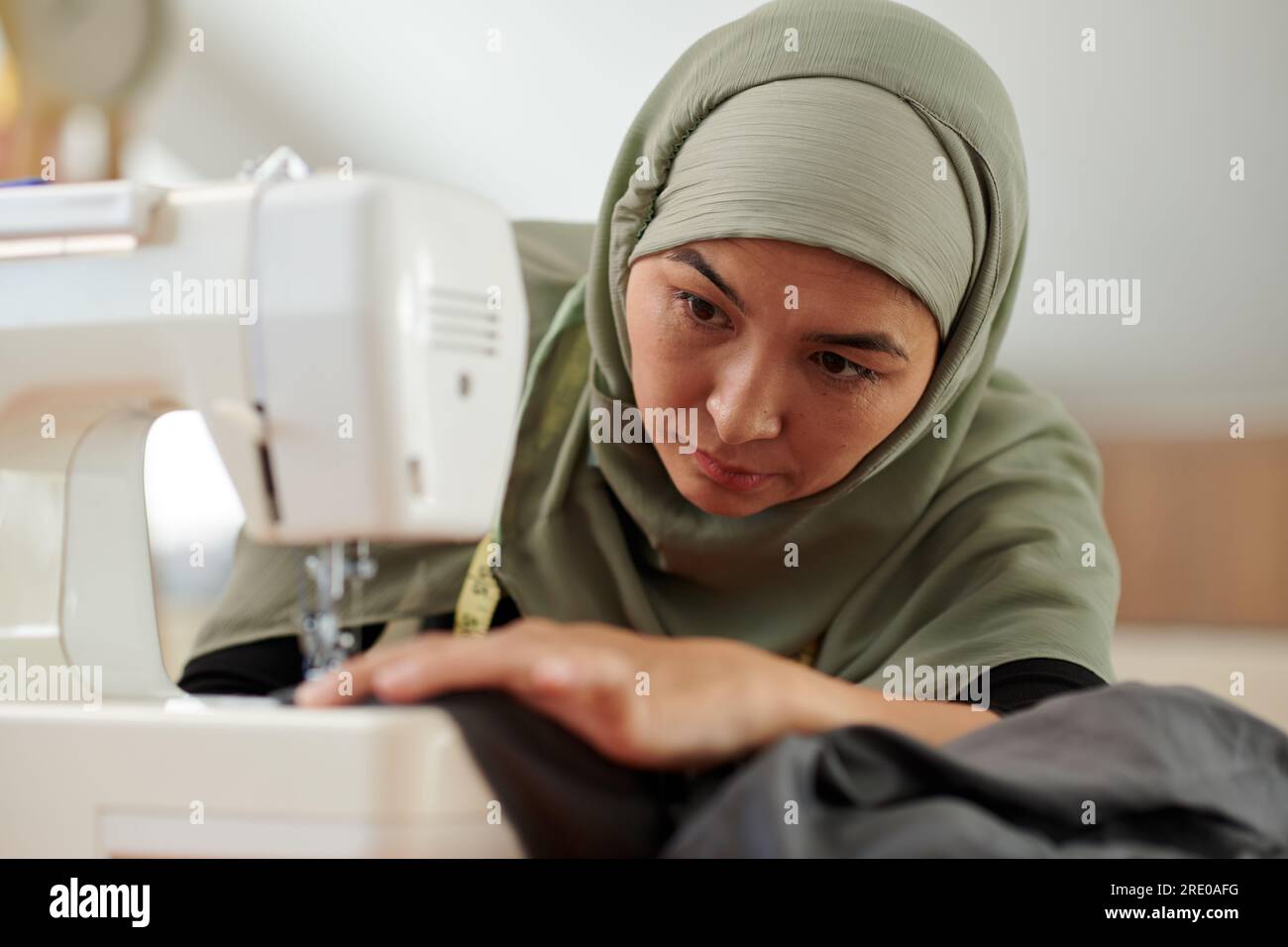 Muslim tailor in hijab sewing garment for client Stock Photo - Alamy