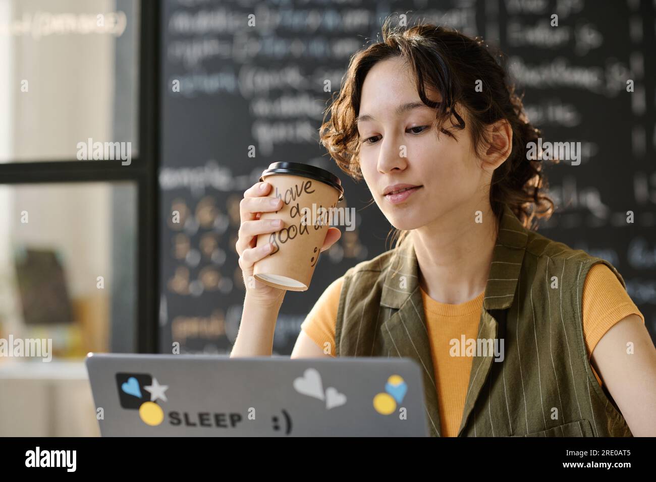 Student sitting at desk in the classroom and drinking coffee during ...