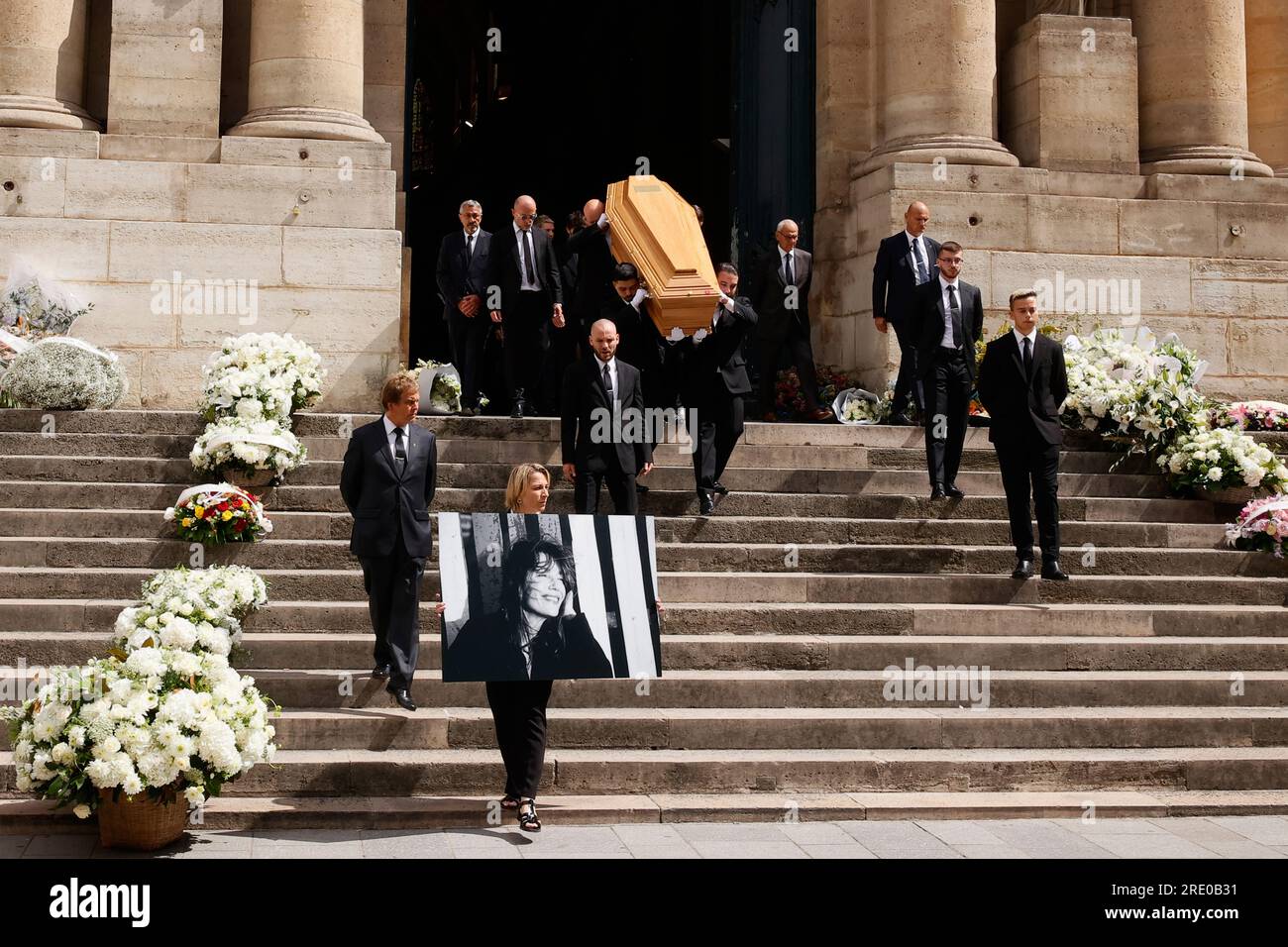 A person holds a portrait of Jane Birkin as pallbearers carry Jane ...