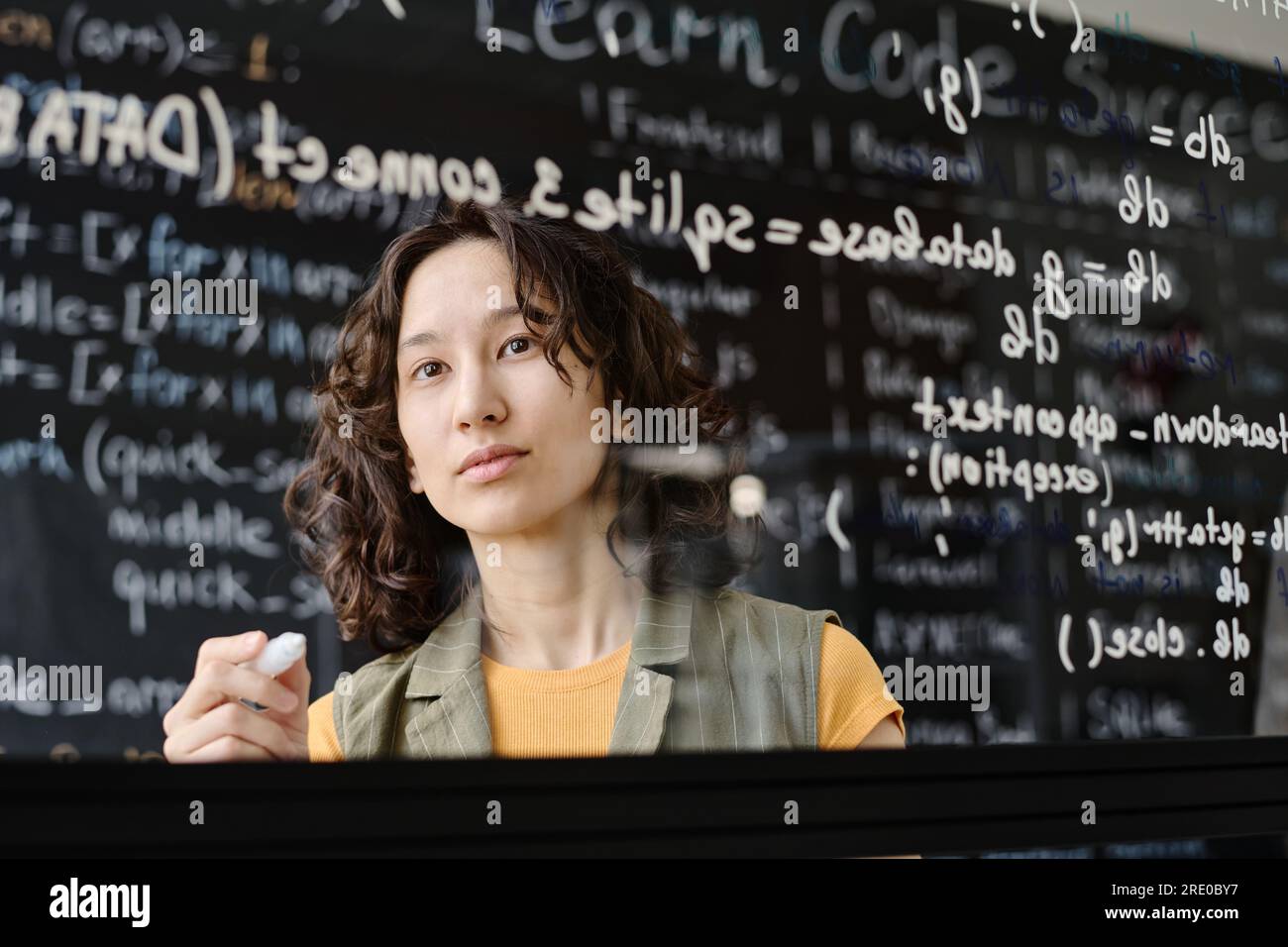 Student writing codes on blackboard during IT lesson in the classroom ...