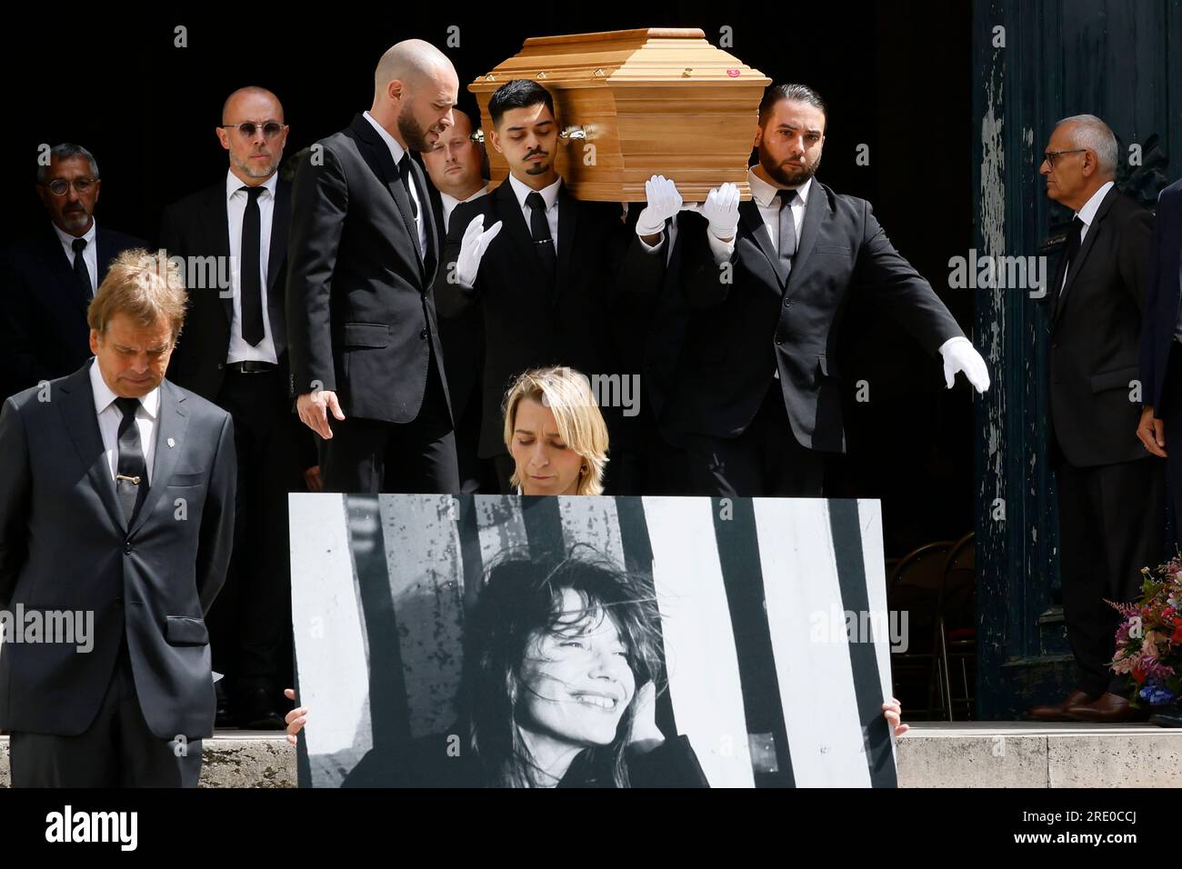 A person holds a portrait of Jane Birkin as pallbearers carry Jane ...