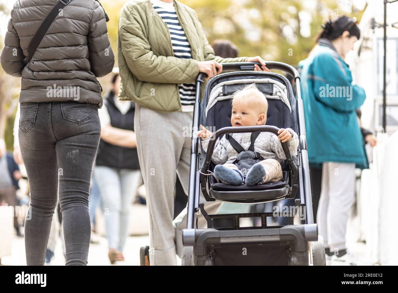 Mother walking and pushing his infant baby boy child in stroller in ...