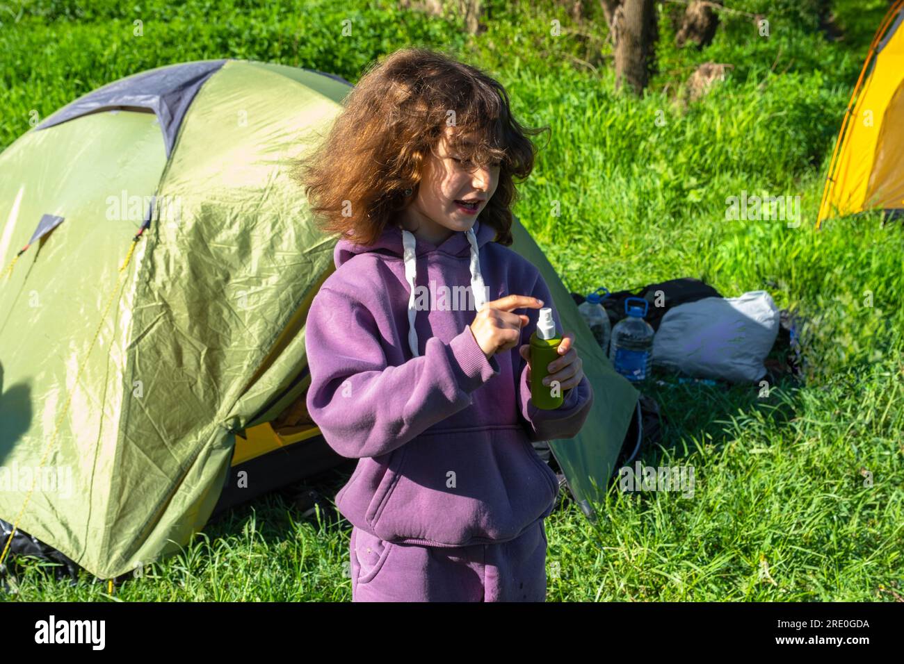 Girl sprays mosquito spray on the skin in nature that bite her hands ...