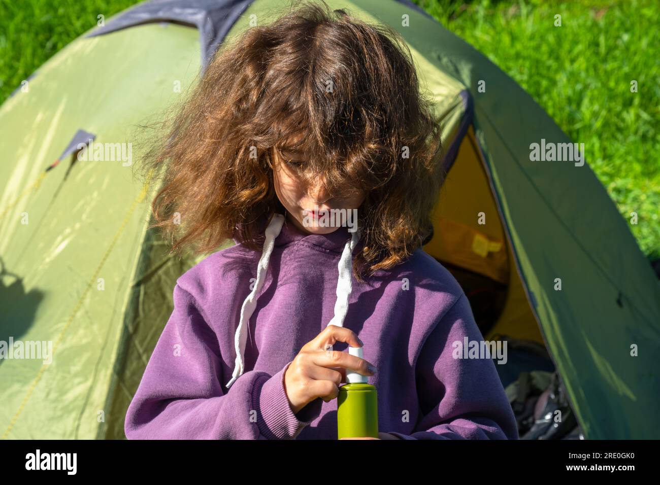 Girl sprays mosquito spray on the skin in nature that bite her hands ...