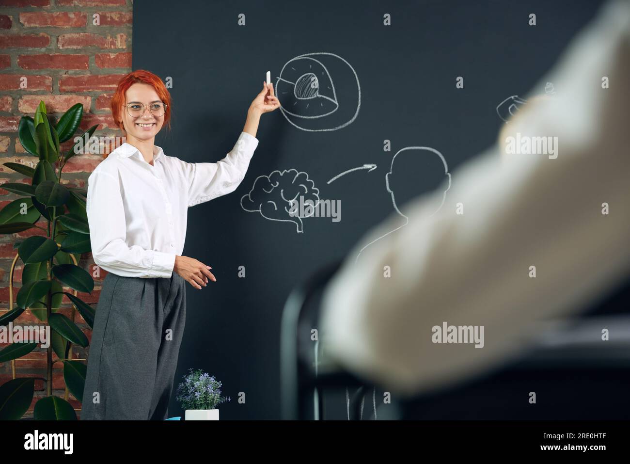 Young redhead woman, teacher standing at chalkboard and teaching ...